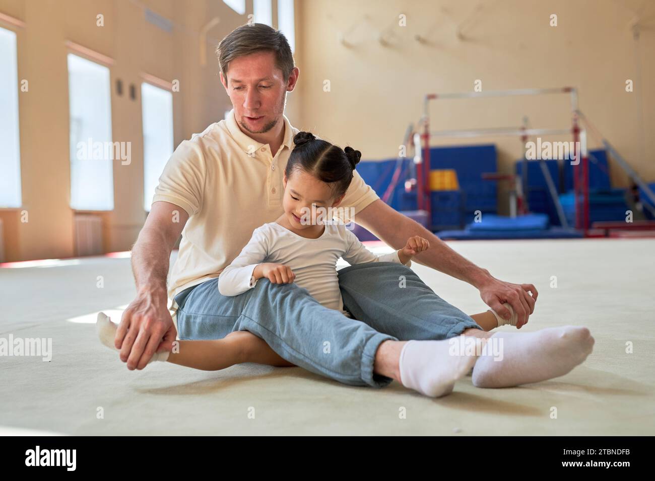 Focused Trainer Helping Girl with Side Split Stretch Stock Photo - Alamy