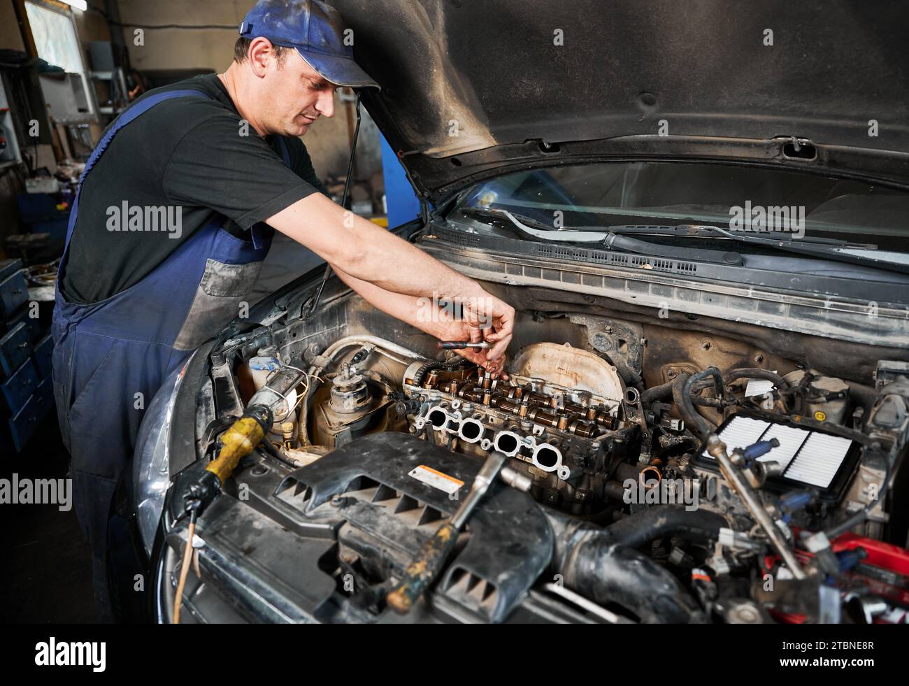 Side view of mechanic repairing car engine, working in garage, workshop ...