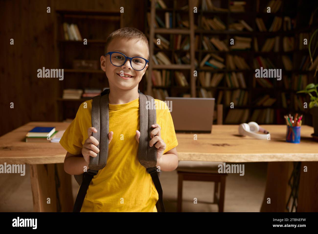 Portrait of little boy student with backpack over home library ...