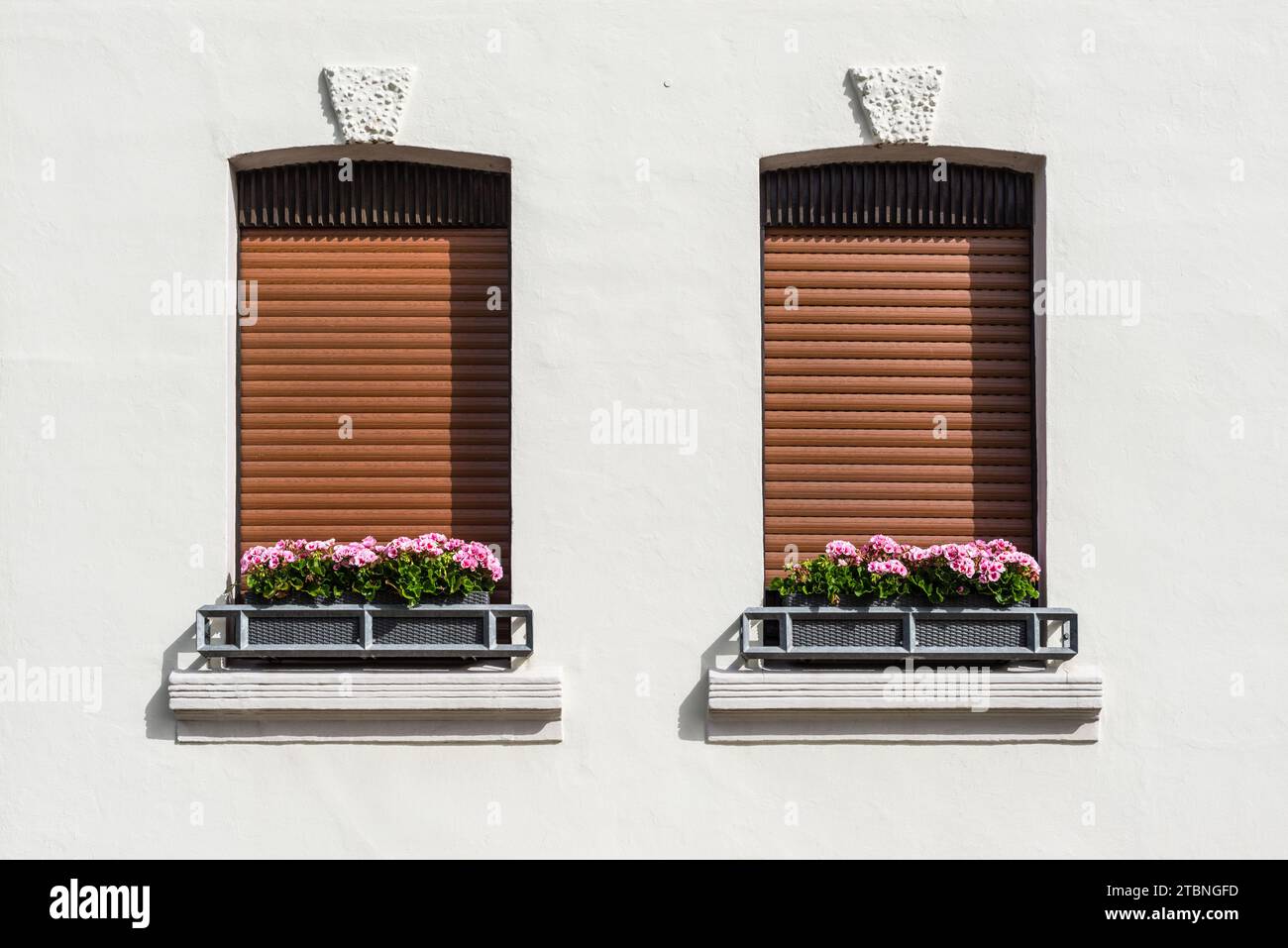 House with white walls and a pair of windows and colorful flowers in ...