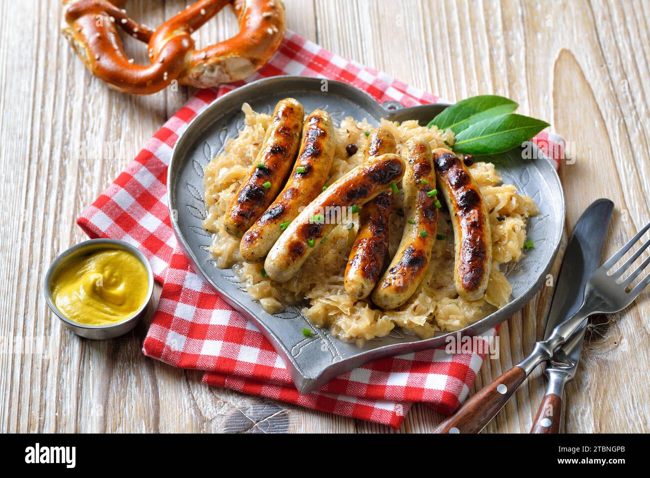 Six fried Nuremberg sausages with sauerkraut on a heart-shaped pewter ...
