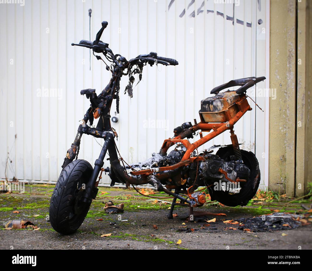 Burnt and charred remains of a moped in front of garage door Stock ...