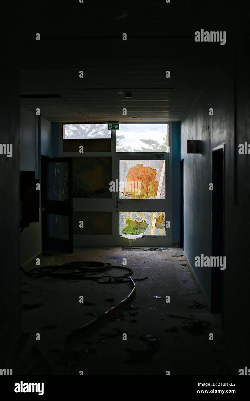 Hallway of abandoned building with a shattered glass door Stock Photo ...