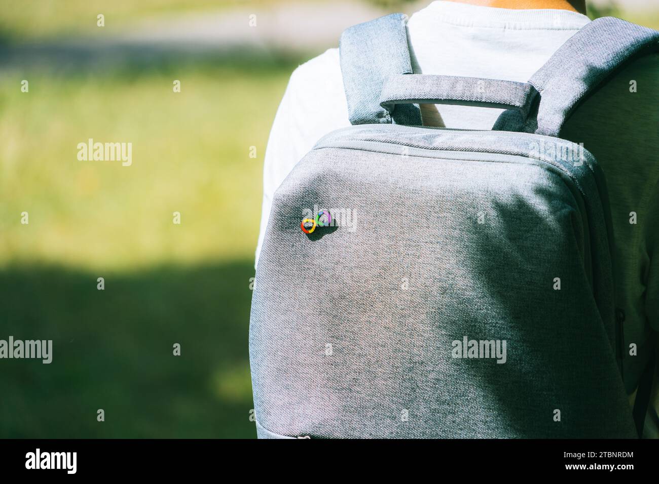 Teenage boy with gray backpack with autism infinity rainbow symbol sign ...