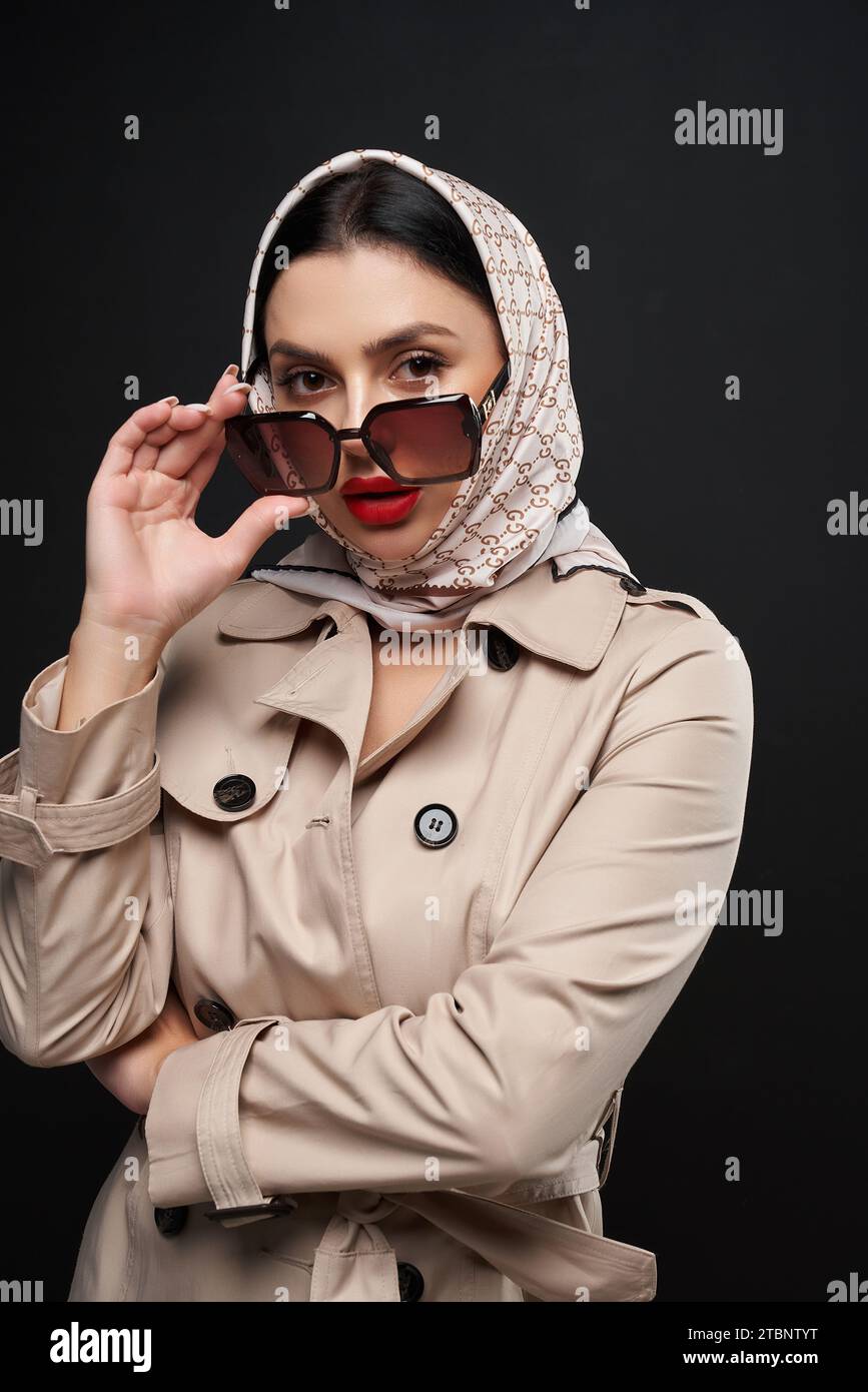 Elegant caucasian lady peering over sunglasses at camera indoors ...
