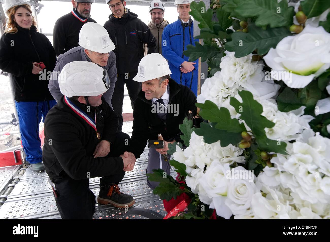 French President Emmanuel Macron, center, meets workers by a bouquet of ...