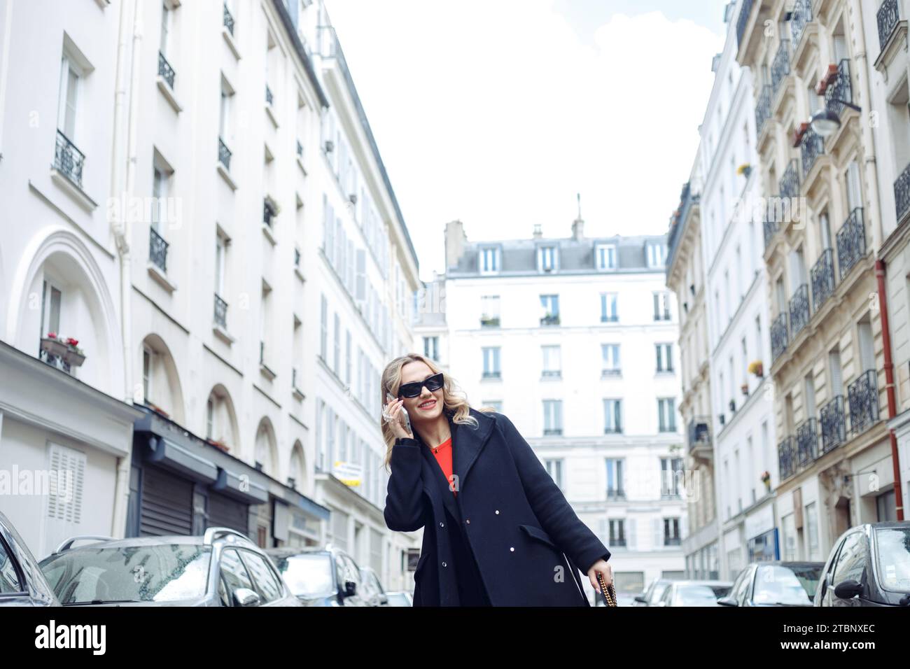 Stylish business lady in black coat, sunglasses talking on phone ...