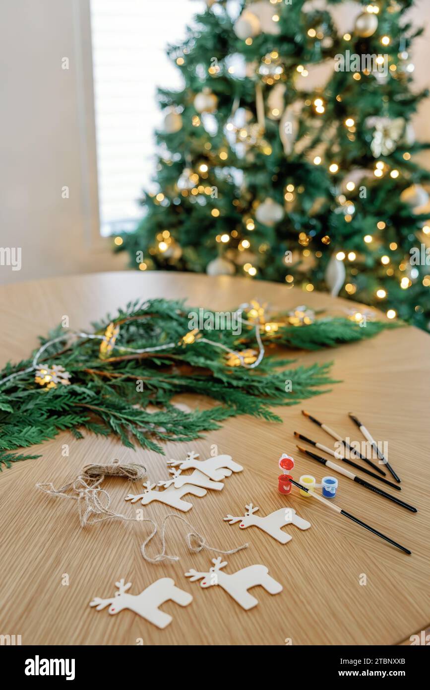 Festive craft supplies, twinkling tree in backdrop Stock Photo - Alamy