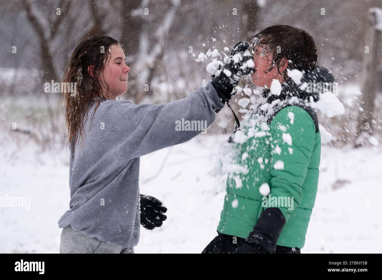 Boy pushing snow into brothers face Stock Photo - Alamy