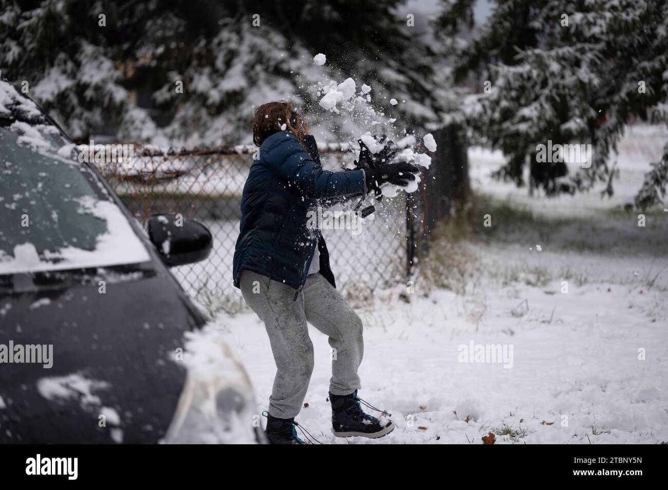 Teen boy getting hit with a snowball near black car Stock Photo - Alamy