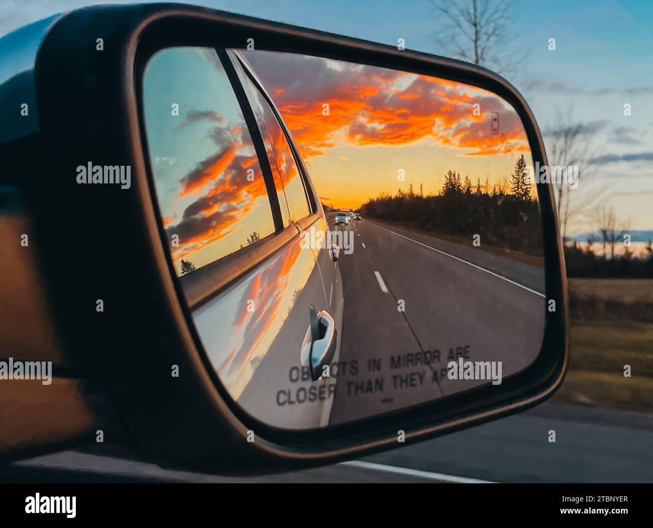 Sunset reflected in side mirror of vehicle on tree lined road Stock ...