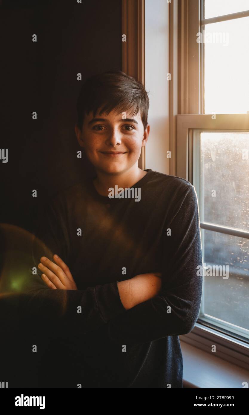 Portrait of happy tween boy leaning against window indoors Stock Photo ...