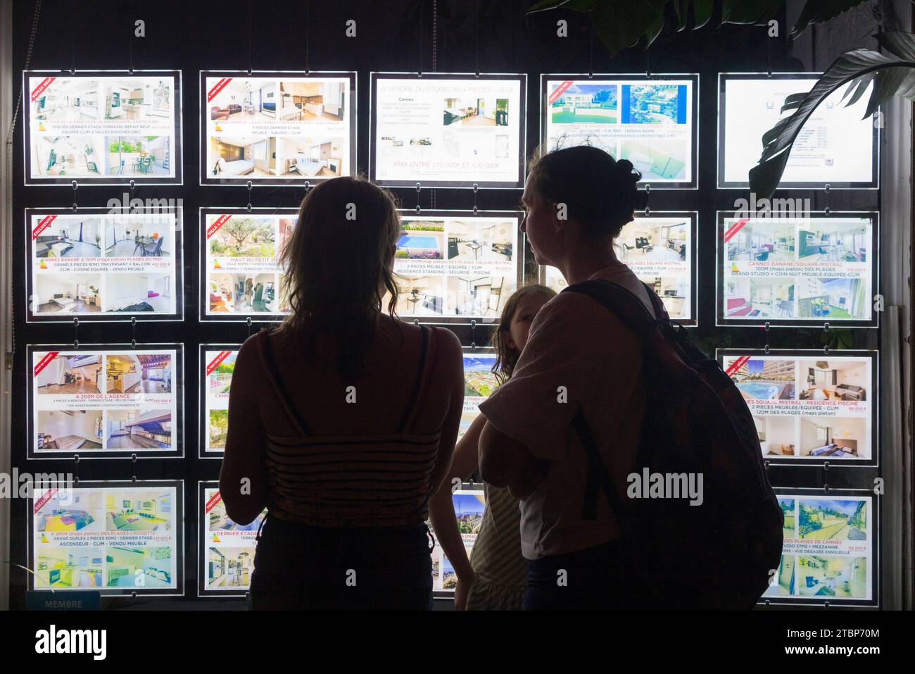 Woman, mum, viewing estate agent window display of property prices of house / houses / apartment ...