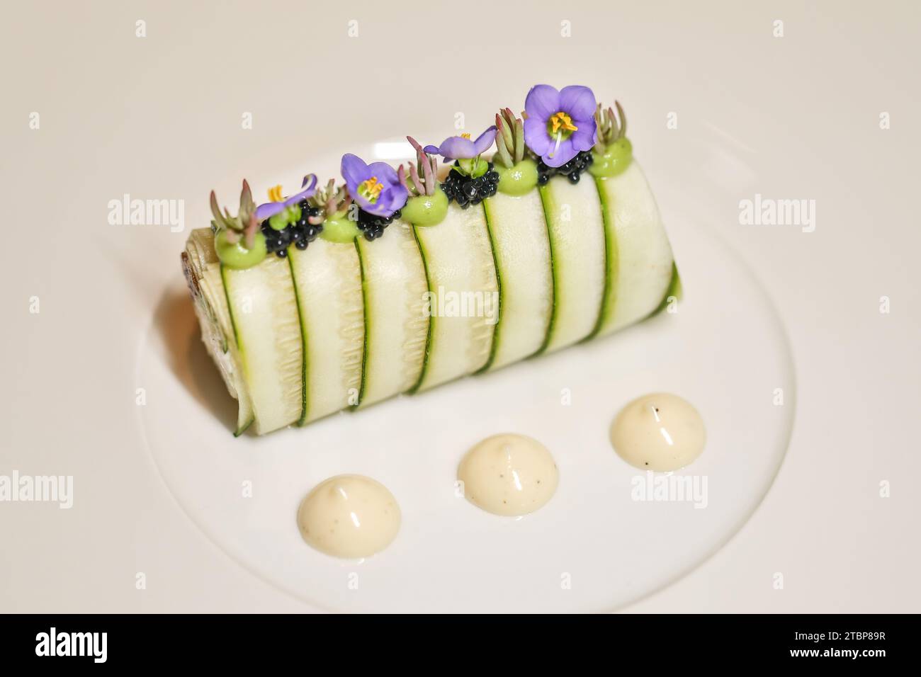 Gourmet cucumber roll with edible flowers and cream sauce. Culinary art ...