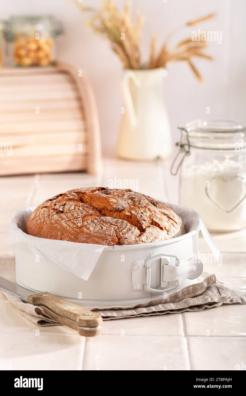 Homemade loaf of round bread with grain and ears. Rustic loaves of ...