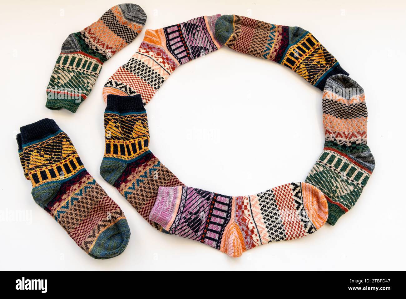 A circle of colourful Winter woollen socks with some outside the circle ...