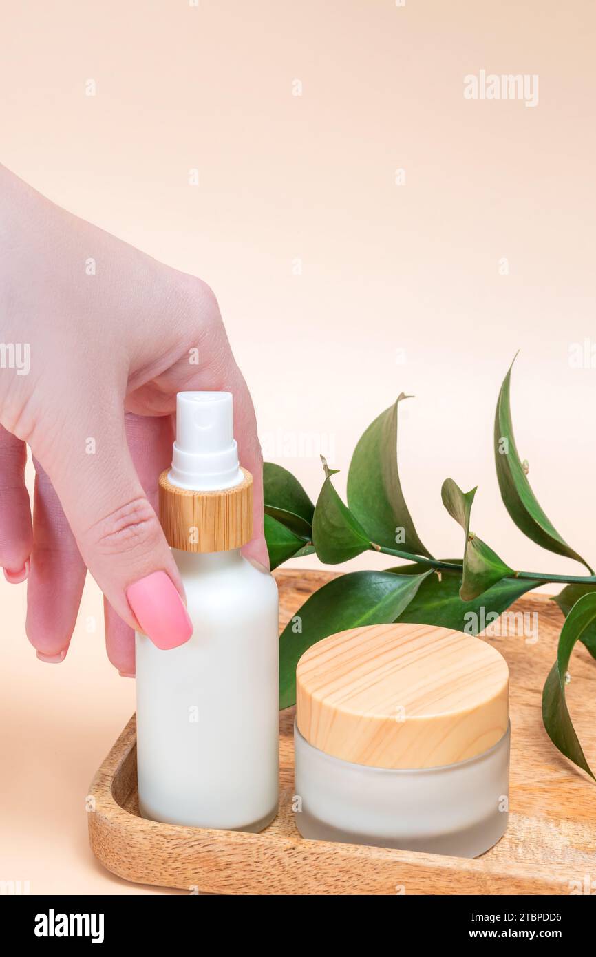 Woman's hand touches a mockup of white bottle of cream. Unlabeled ...