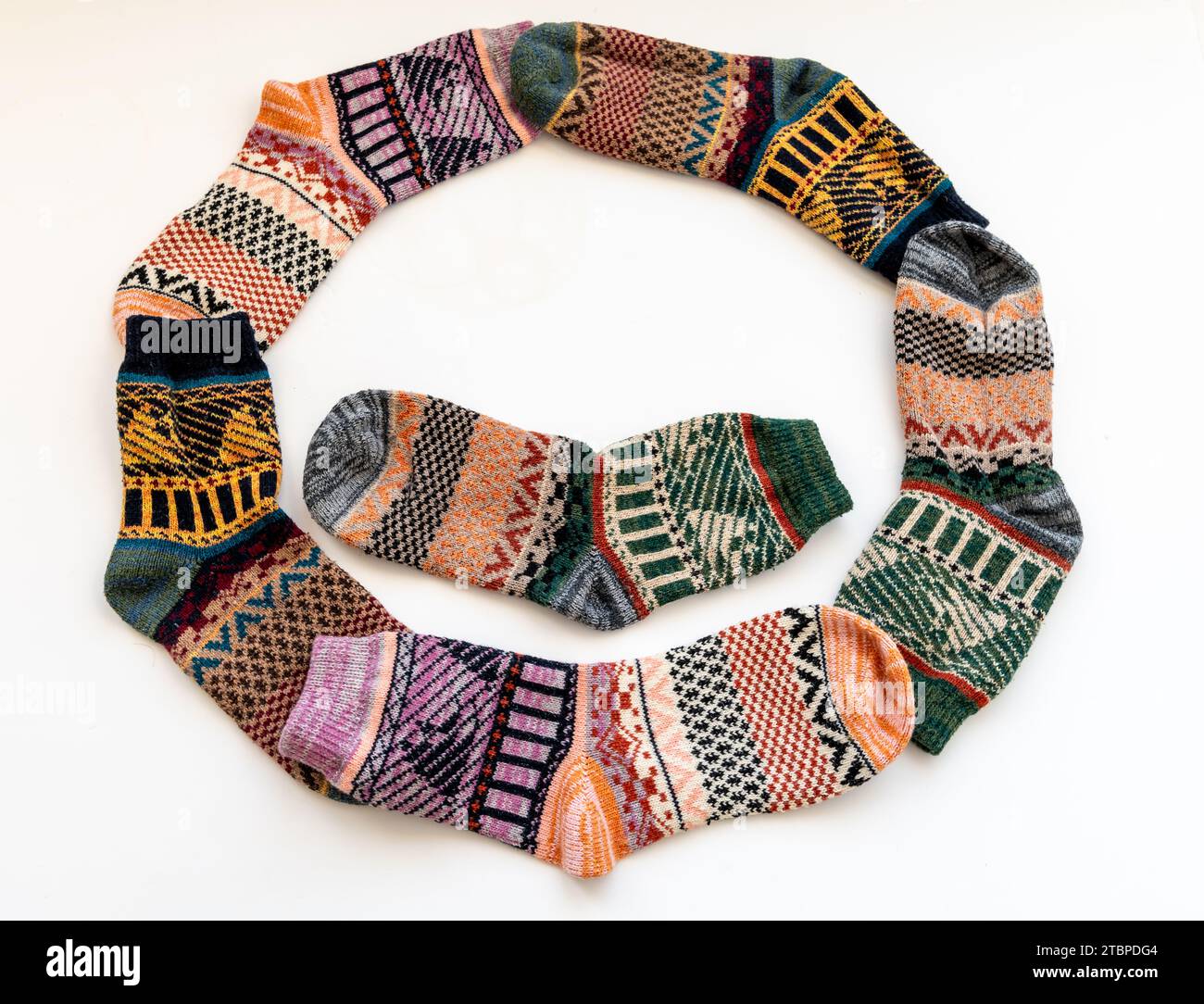 A circle of colourful Winter woollen socks with one inside the circle ...