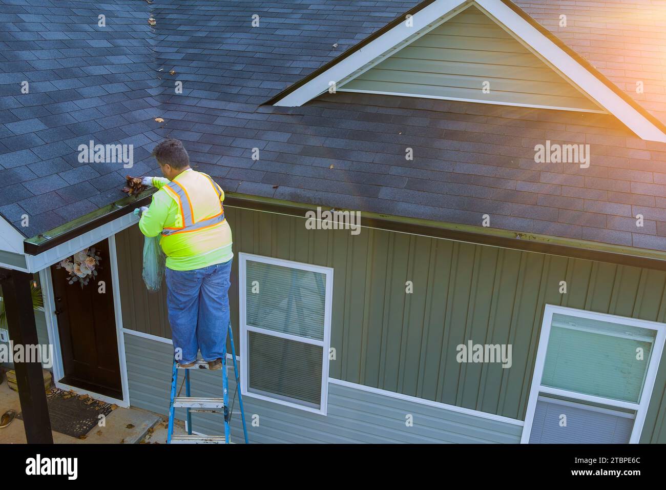 There is worker cleaning clogged roof gutter drain which has been ...