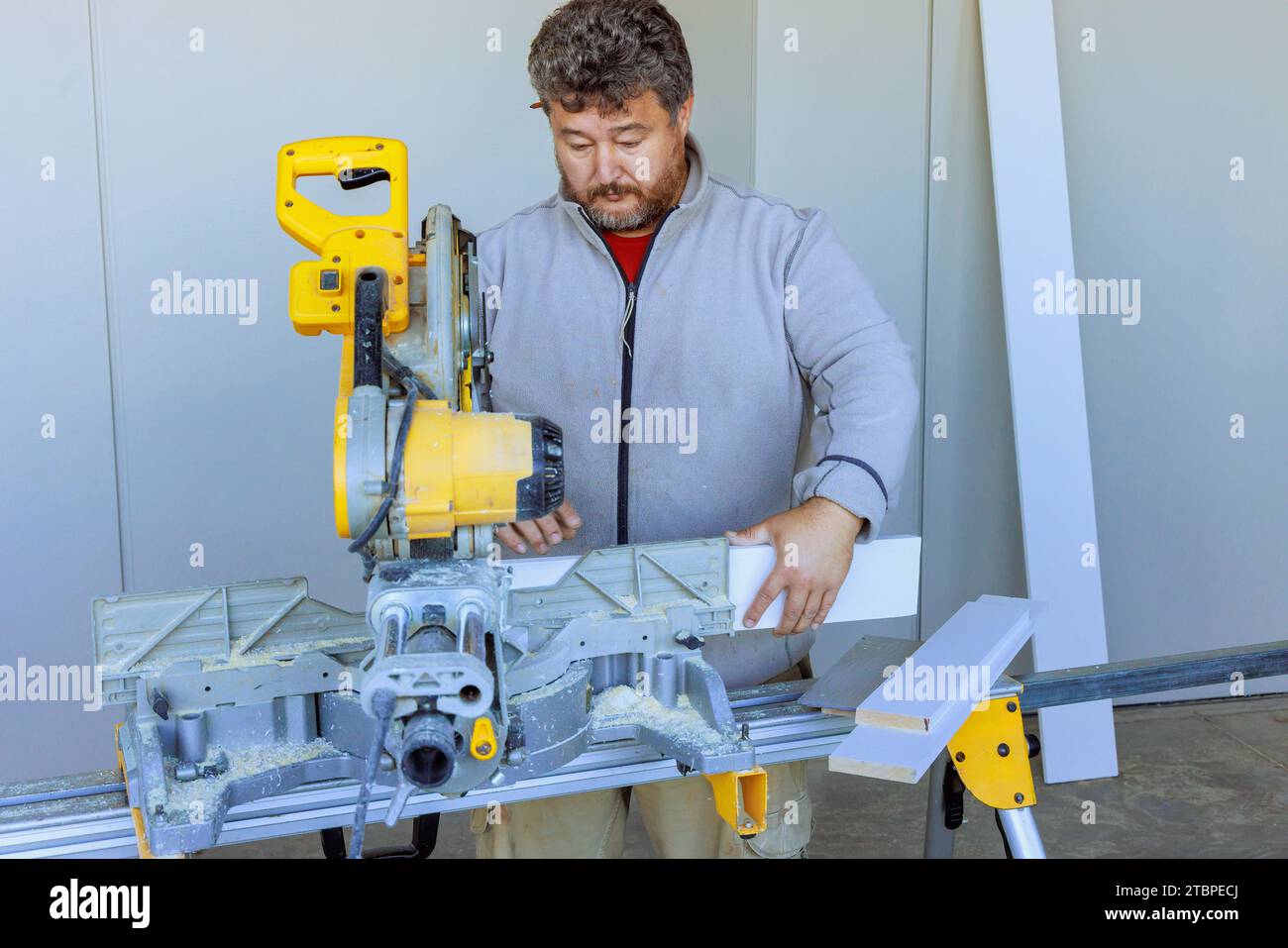 Cutting base moldings with chop saw is task performed by trim worker ...