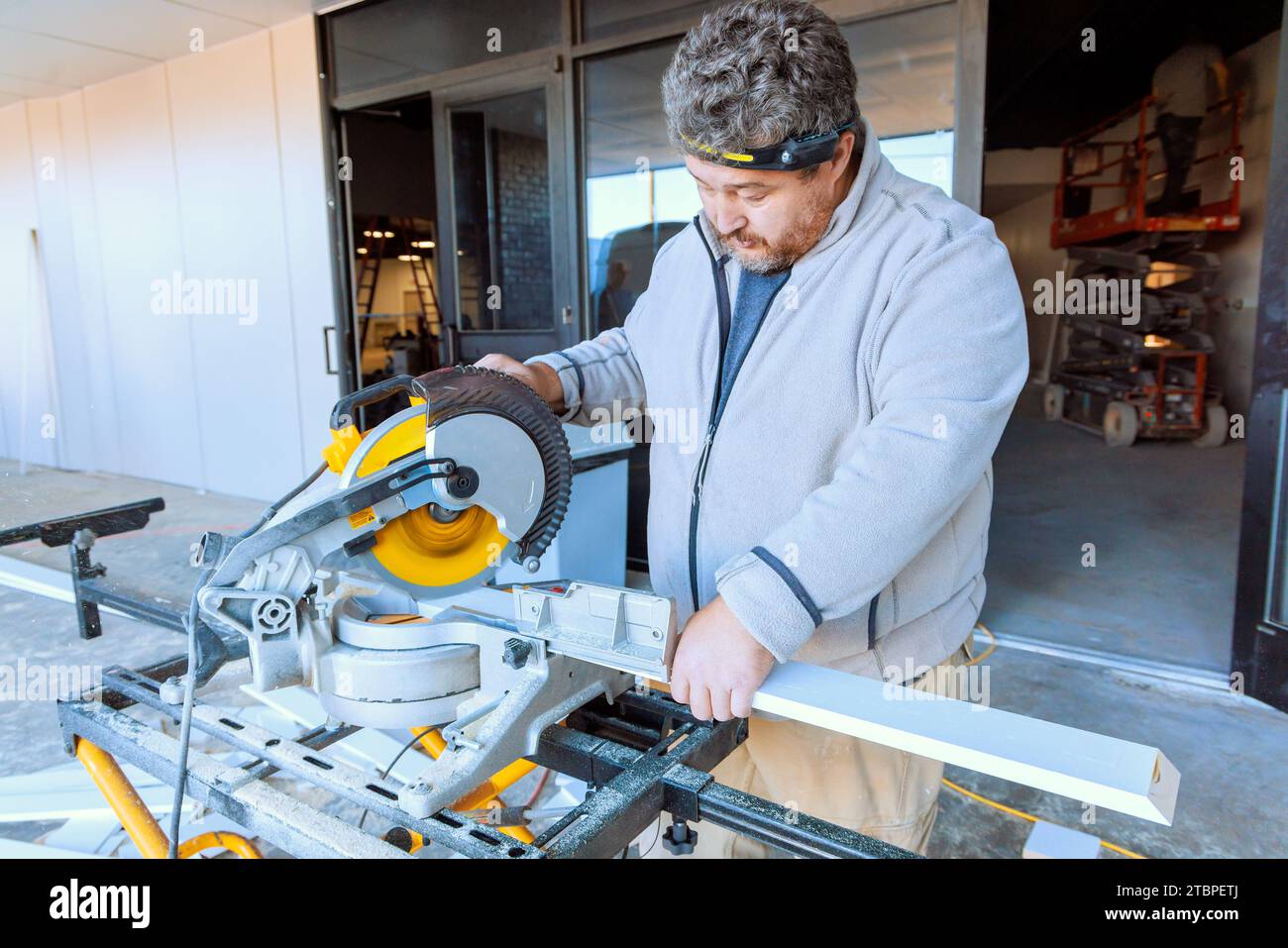 Worker cutting base wooden moldings with chop saw Stock Photo - Alamy