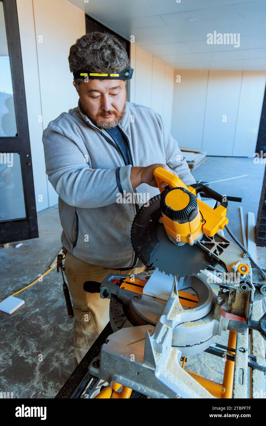 Trim worker using chop saw to cuts wooden base moldings Stock Photo - Alamy