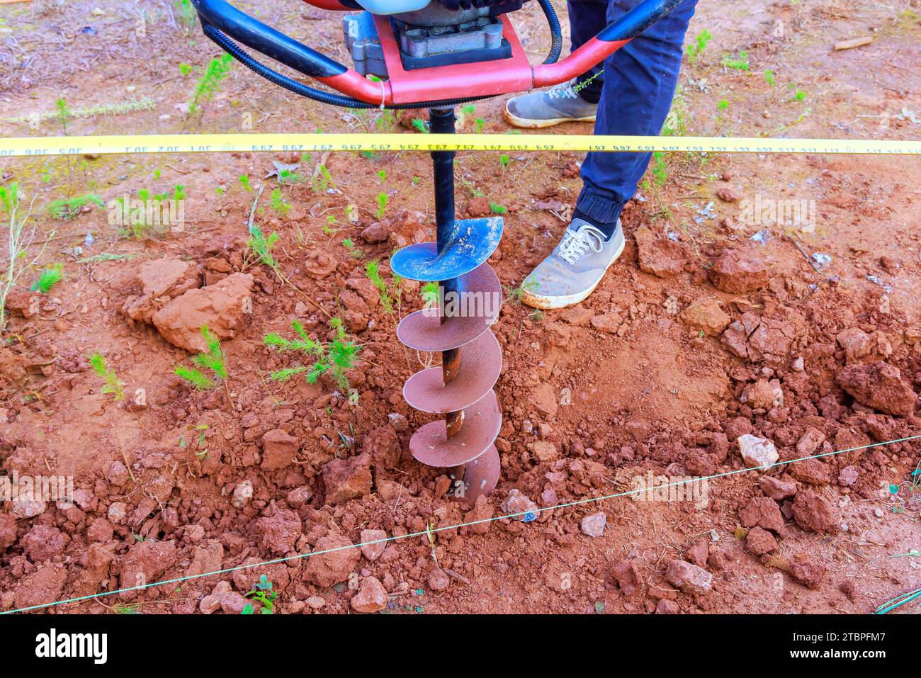 With gasoline drilling machine, worker digs ground in preparation for ...