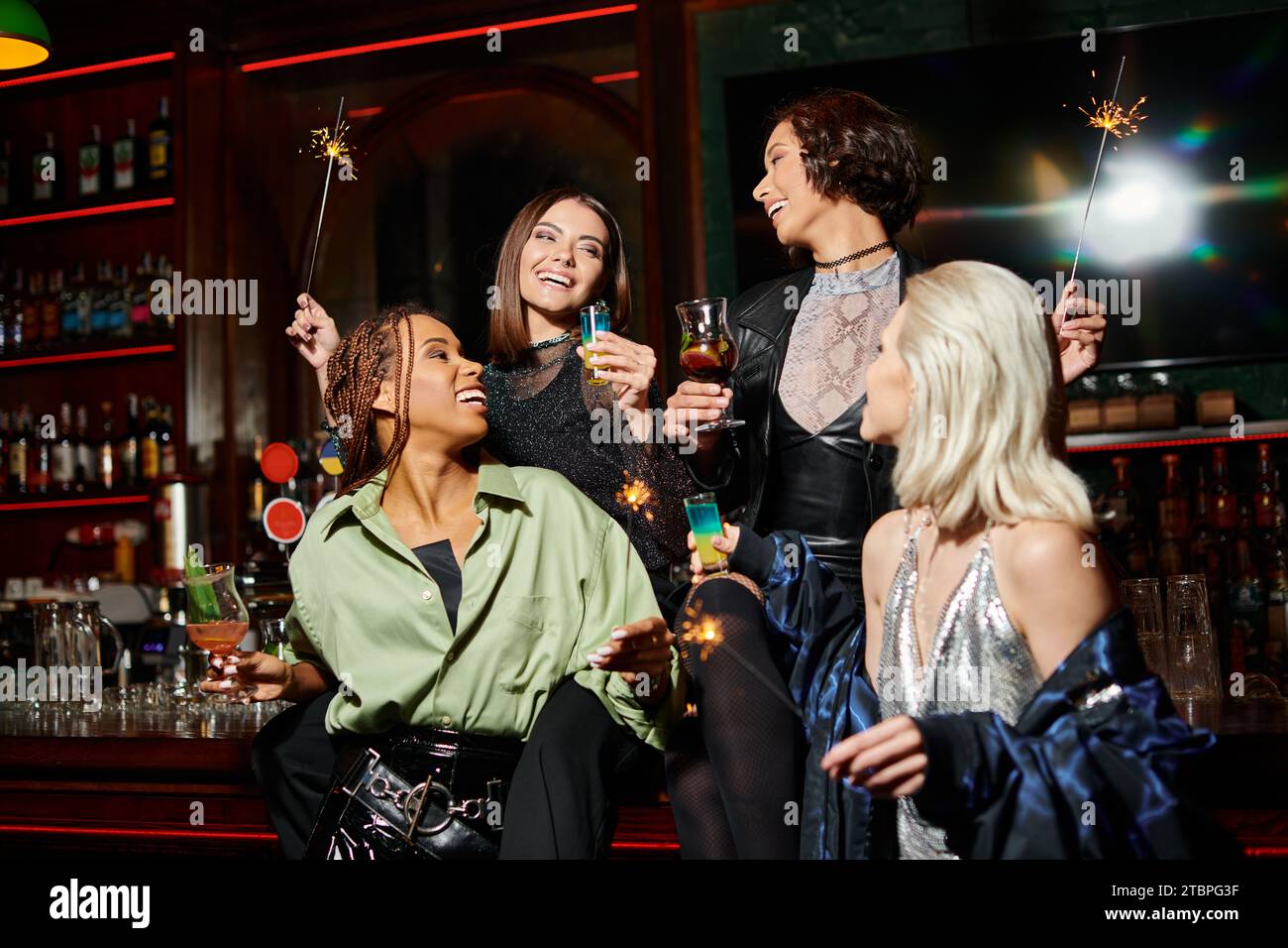 fashionable and happy multiracial girlfriends with cocktails and shiny ...