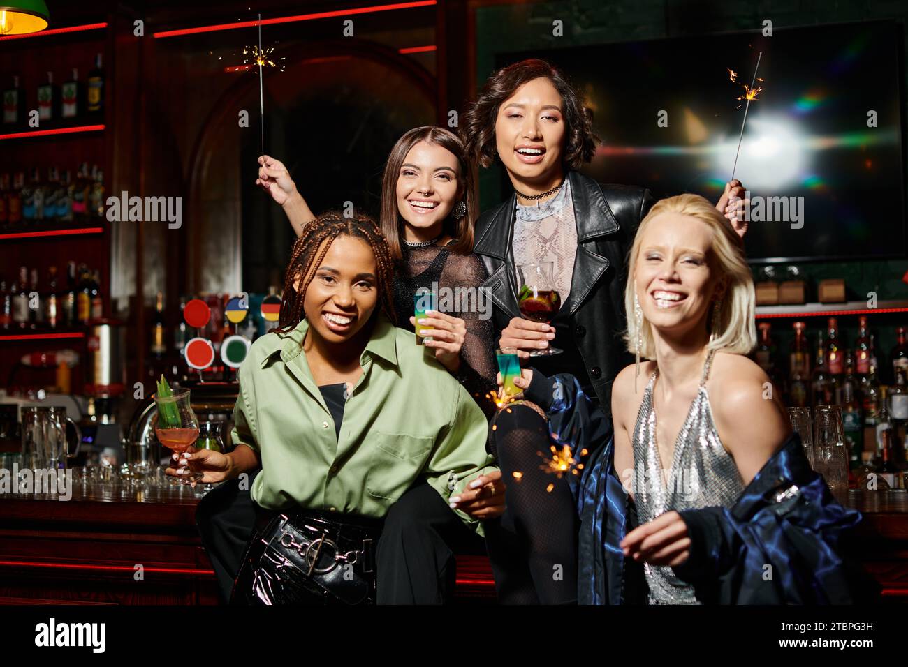 cheerful stylish multiracial girlfriends with cocktails and shiny ...