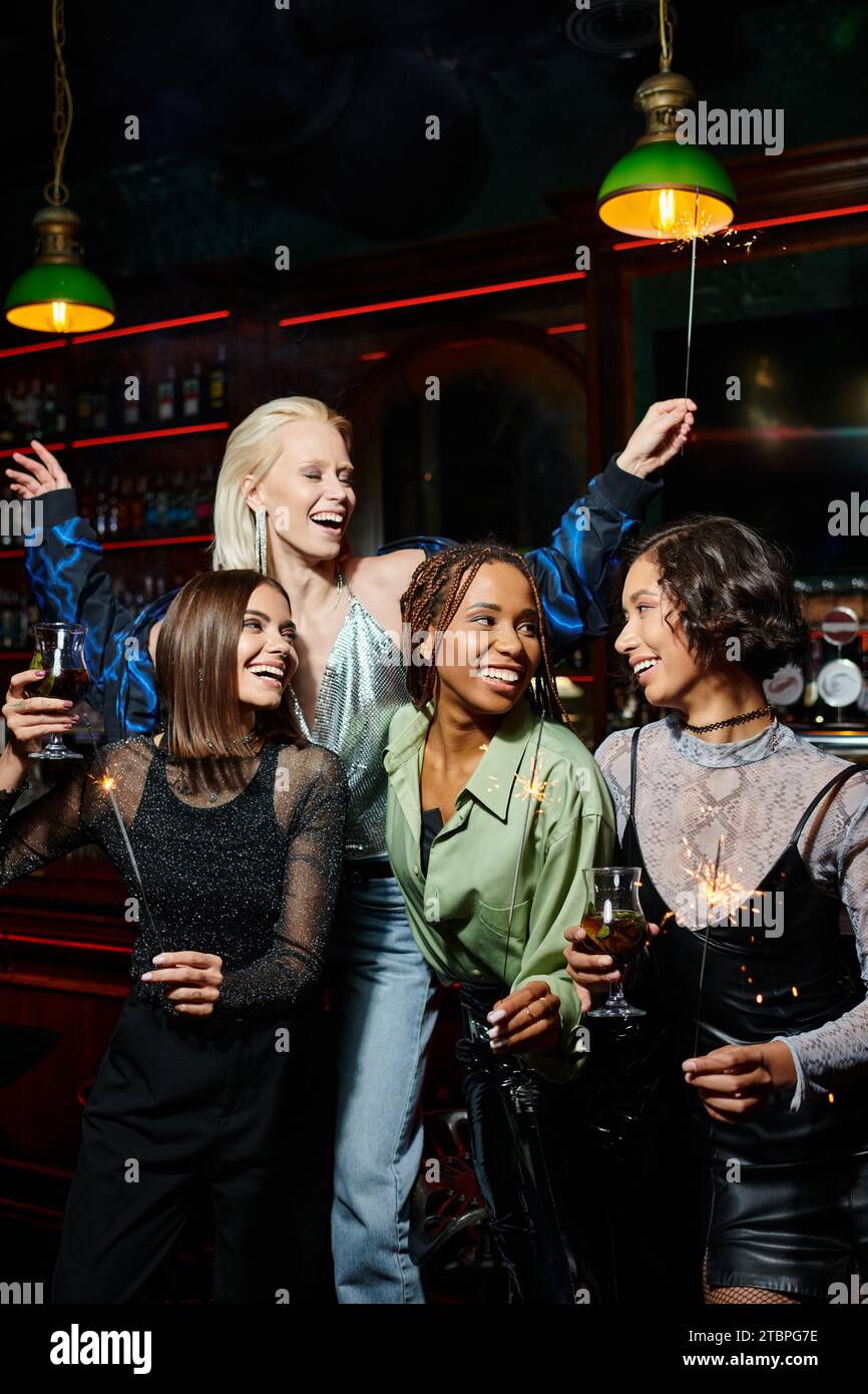cheerful multiethnic girlfriends with cocktails and festive sparklers ...