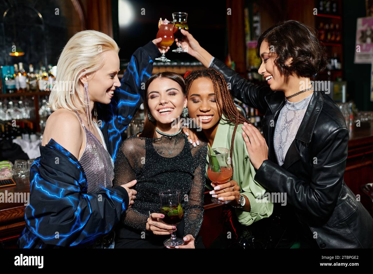 overjoyed multiracial girlfriends clinking cocktail glasses in modern ...