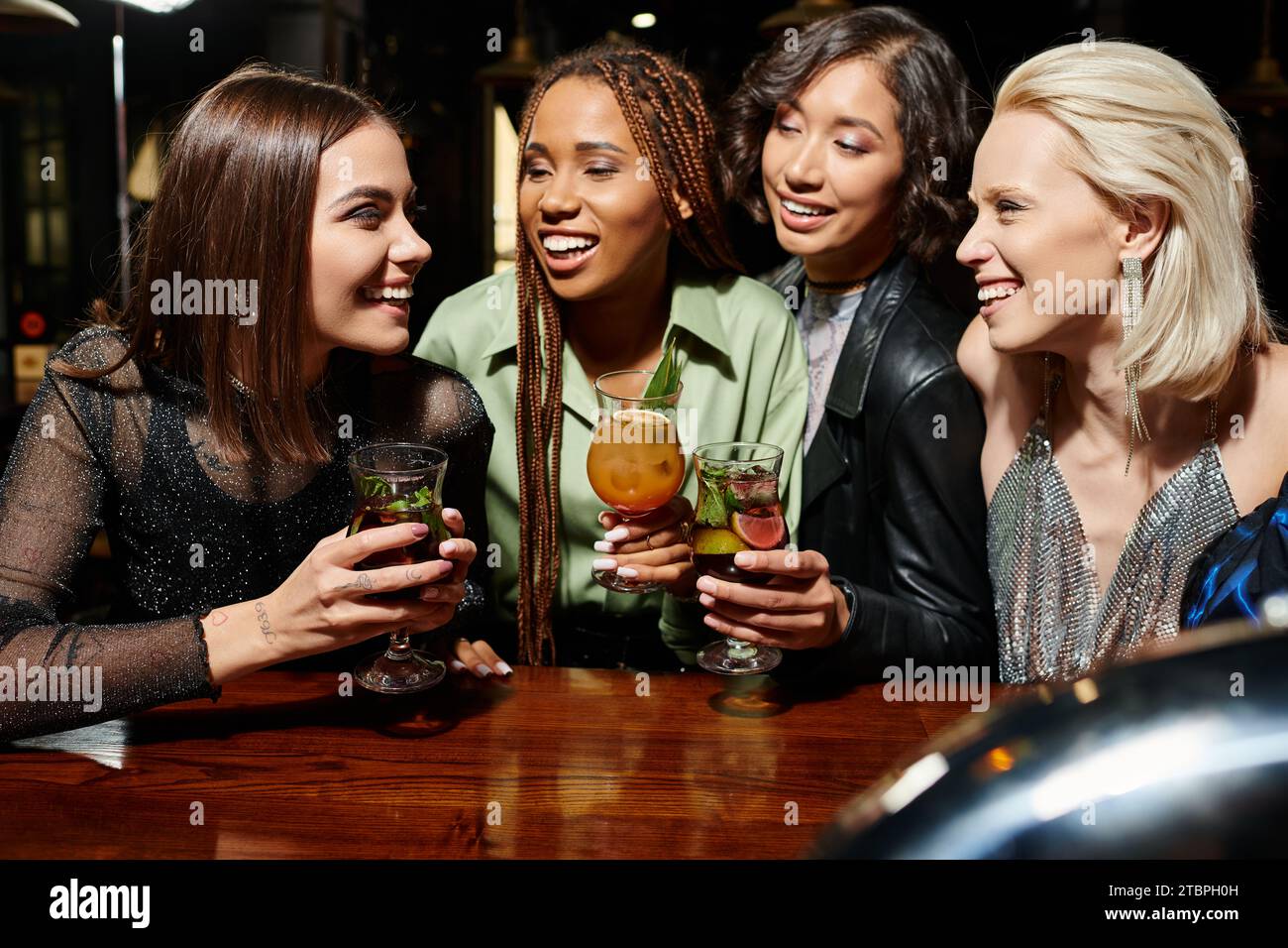 cheerful multiethnic girlfriends with delicious cocktails talking ...