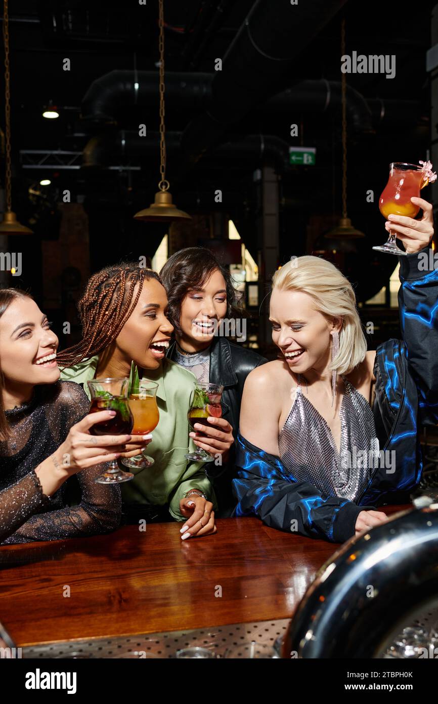excited blonde woman toasting with cocktail during hen party with ...