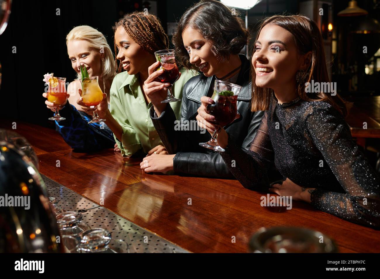 young fashionable multiracial women with delicious cocktails near bar ...