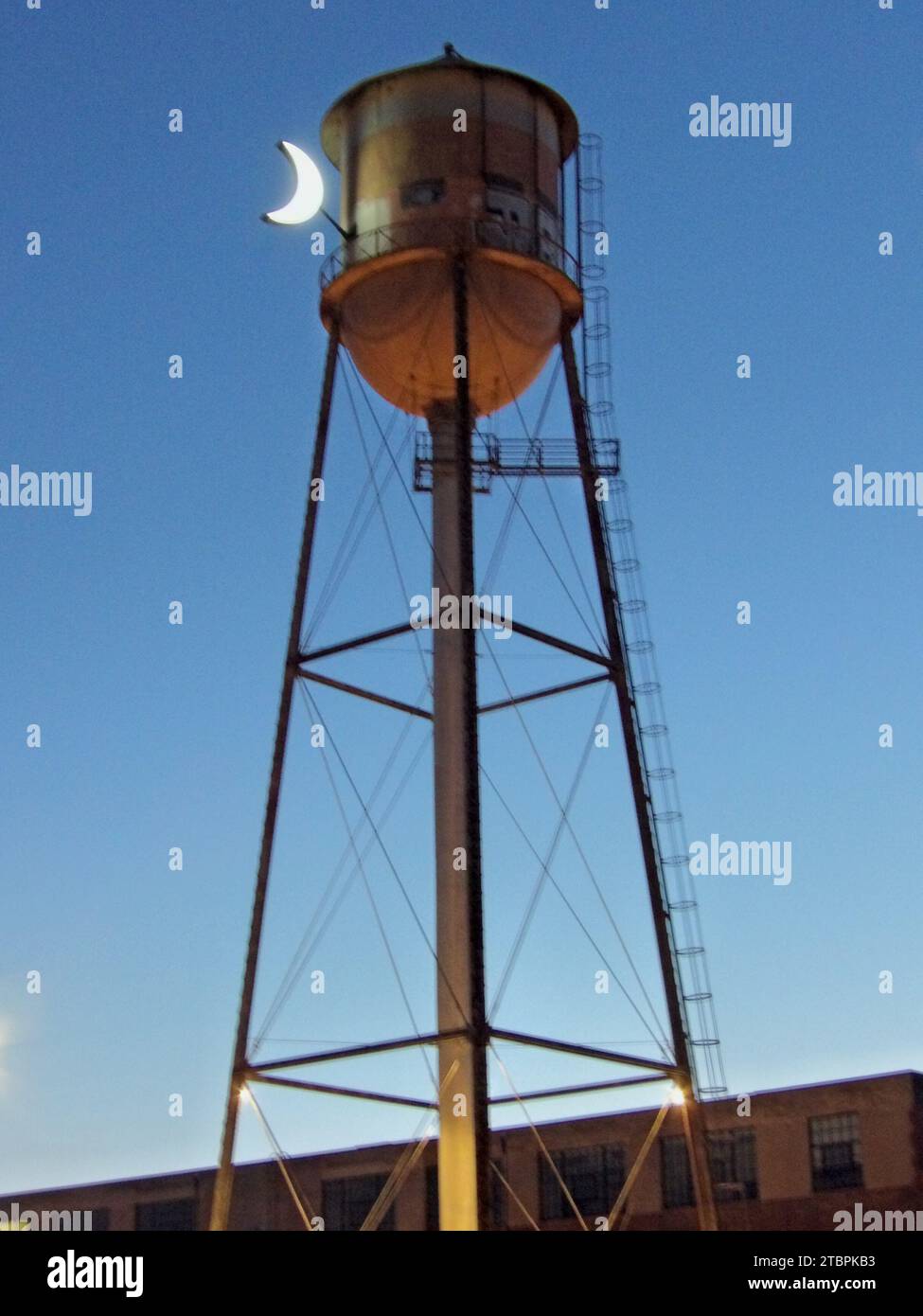 A black and white image of a tall water tower situated in a city ...