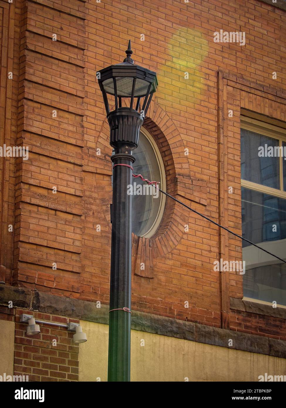 An illuminated black streetlamp is affixed to the side of a ...