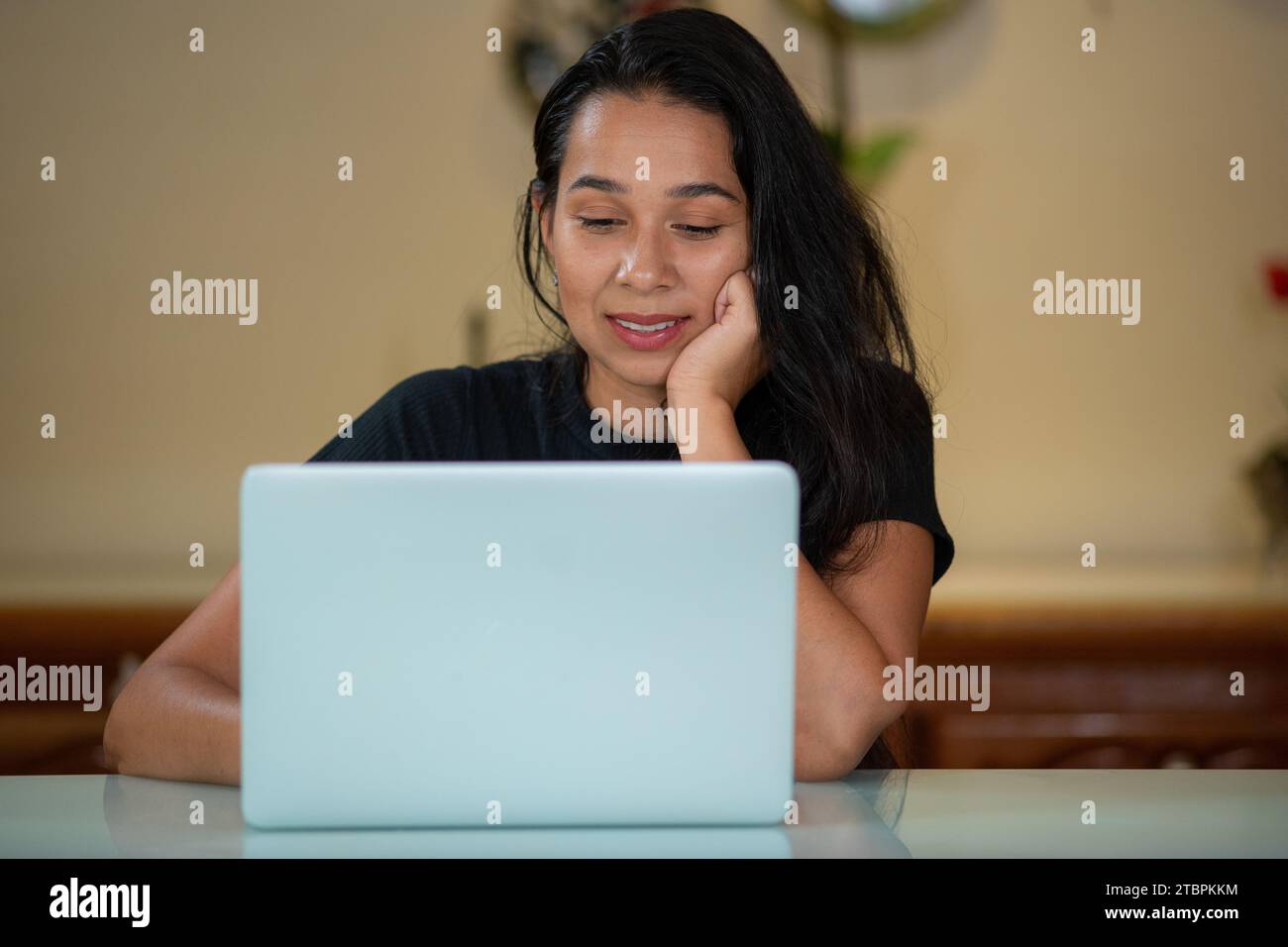 A female professional sitting at a desk in an office, using a laptop ...