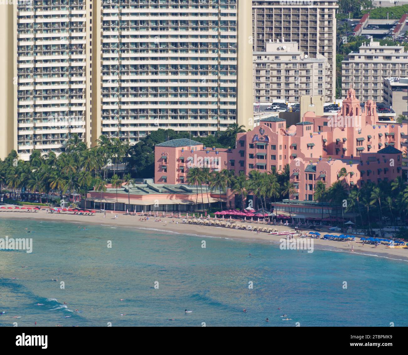 A vibrant pink building is situated atop a sandy beach, with the azure ...