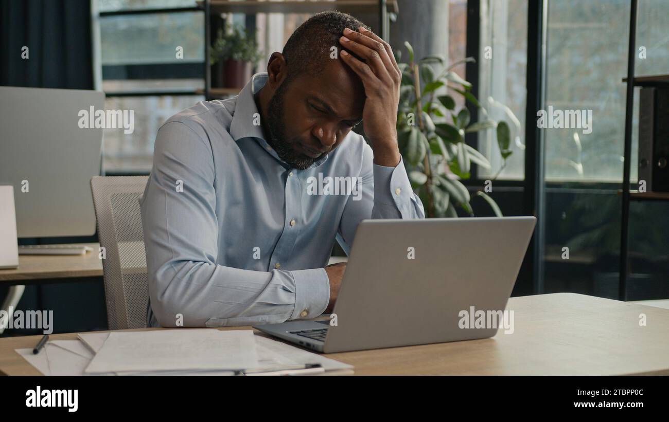 Overworked African American mature man working laptop in office suffer ...