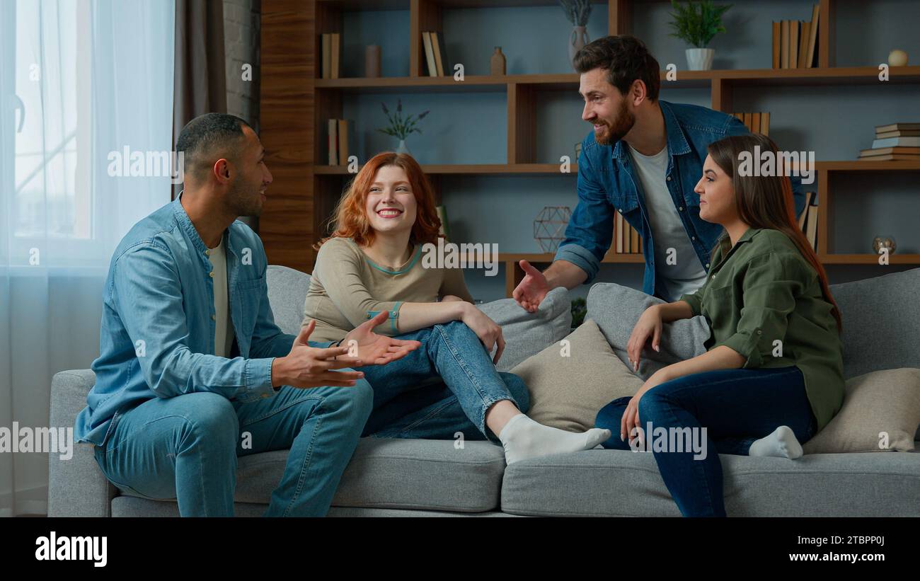 Four ethnic friends fellows companions sit on home couch talking ...
