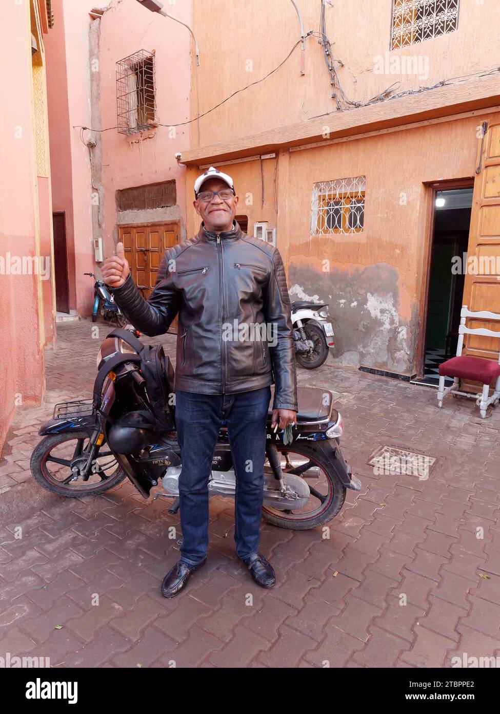 Friedly local biker in leather jacket gives the thumbs up sign in a ...