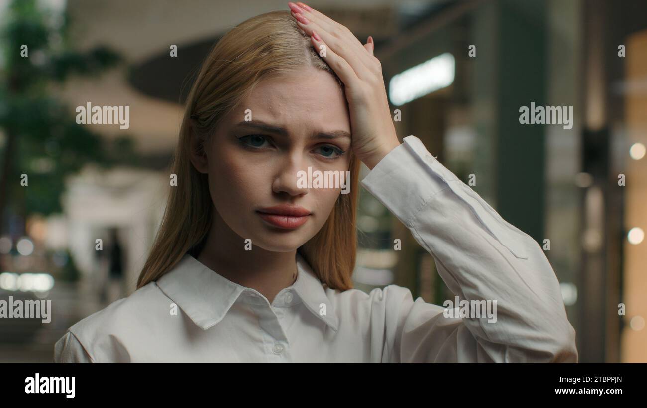 Upset businesswoman in shopping mall touch head worried with business ...