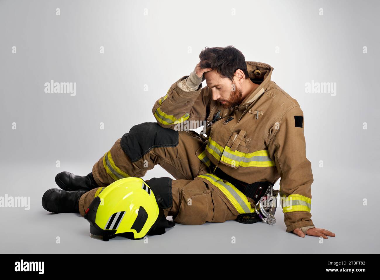 Sad, despaired firefighter crying, rubbing forehead, while sitting on ...