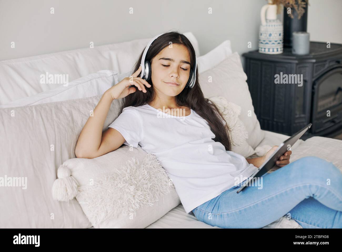 Cute pre-teen girl resting alone in bedroom with digital tablet device ...
