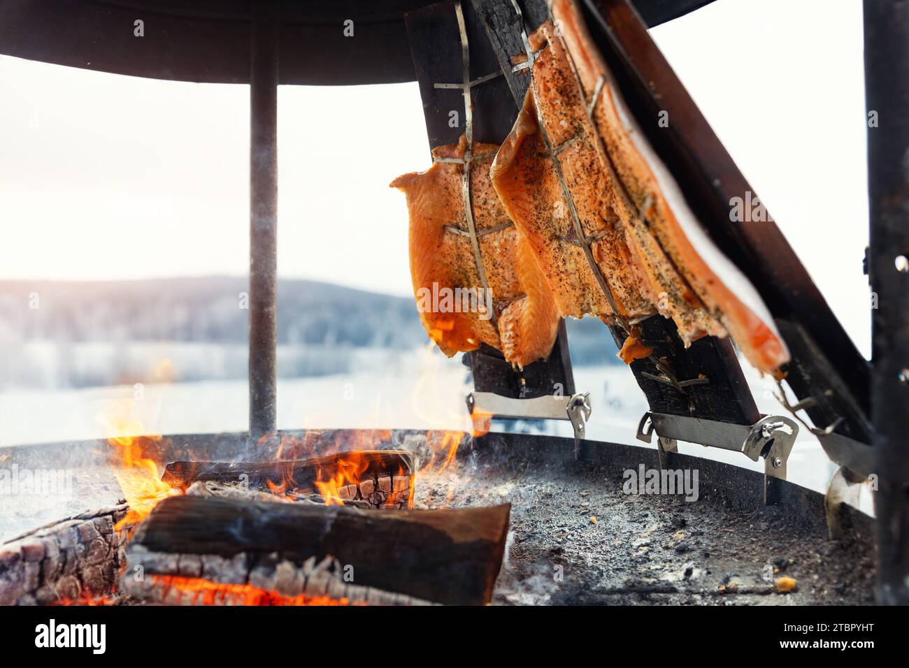 Smoked salmon fish fillet pinned on wooden plank board grilled on open ...