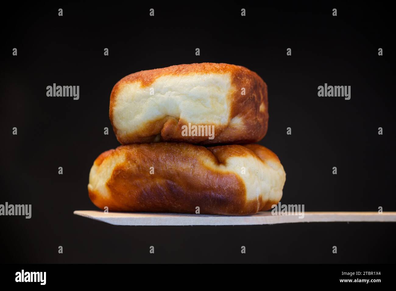 Fried pies filled with yeast dough on a wooden paddle, isolated on a ...