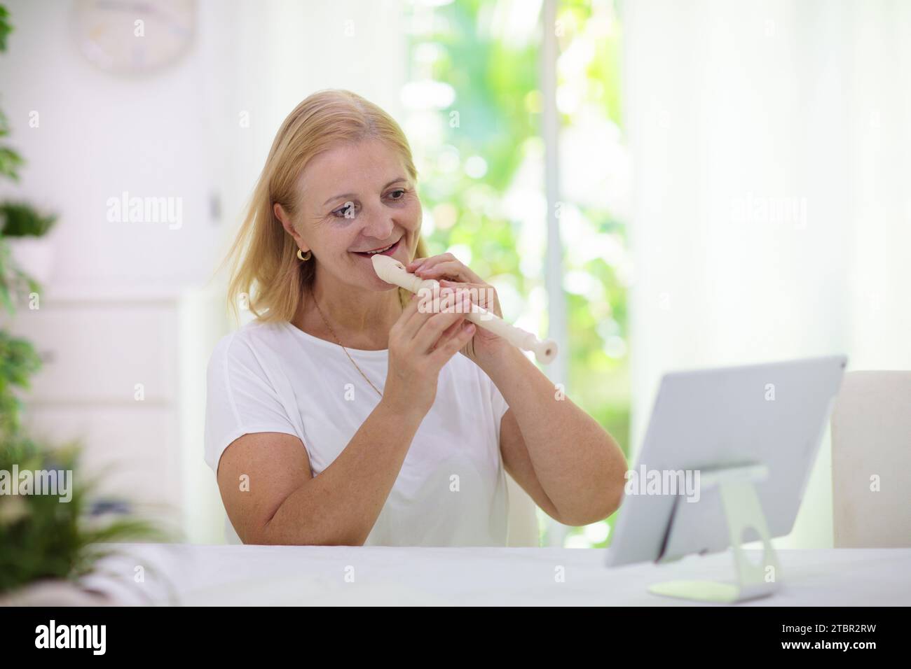 Teacher playing flute in front of computer. Online music tuition ...