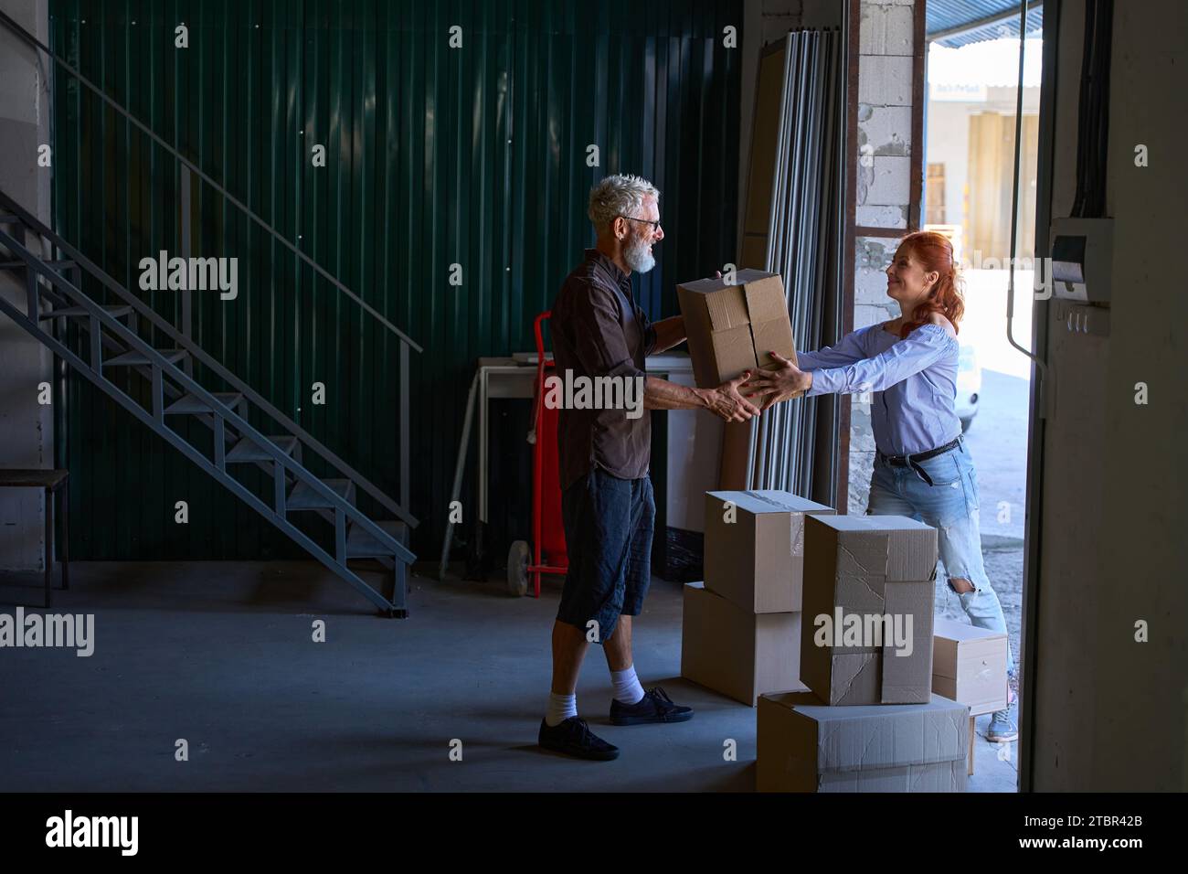 Smiling female helps her husband carry boxes with things Stock Photo ...