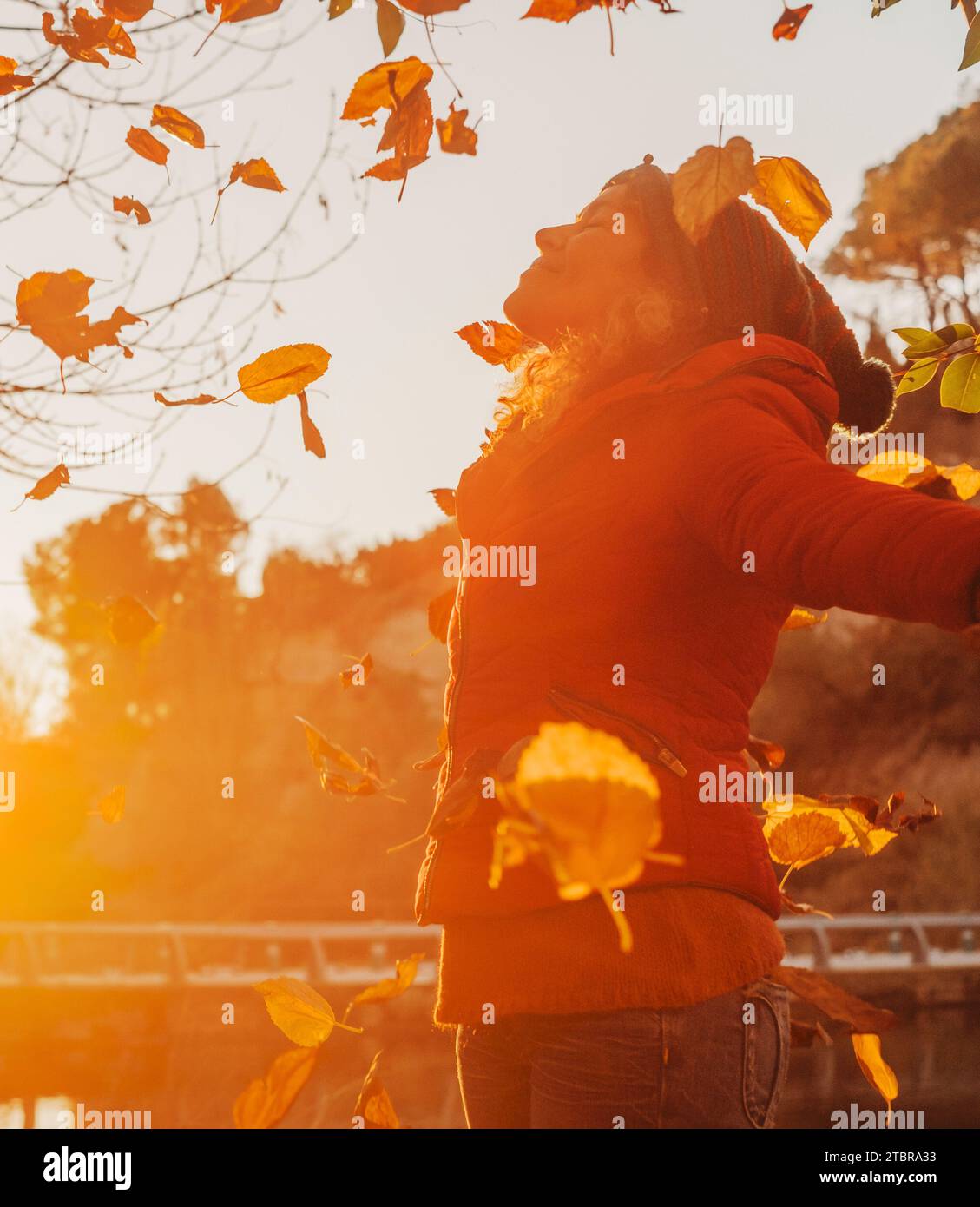 Winter is coming. Autumn sunset and happy woman throwing leaves in the ...
