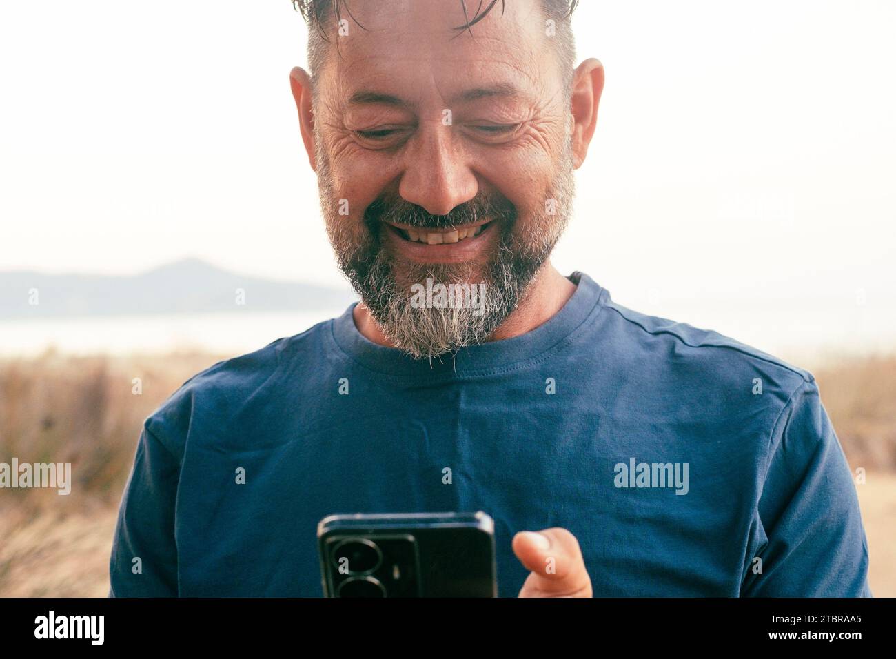 Front view of one casual man using mobile phone with cheerful smile ...